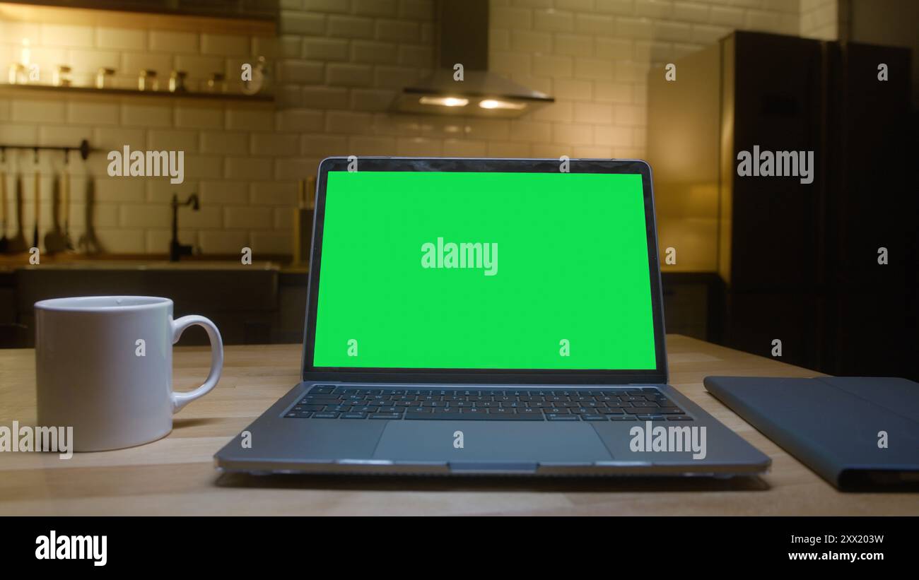 A laptop with a green screen on a kitchen counter with a white coffee ...