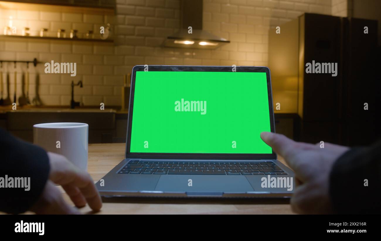 Point of view shot: Man uses laptop computer with green mock up screen ...