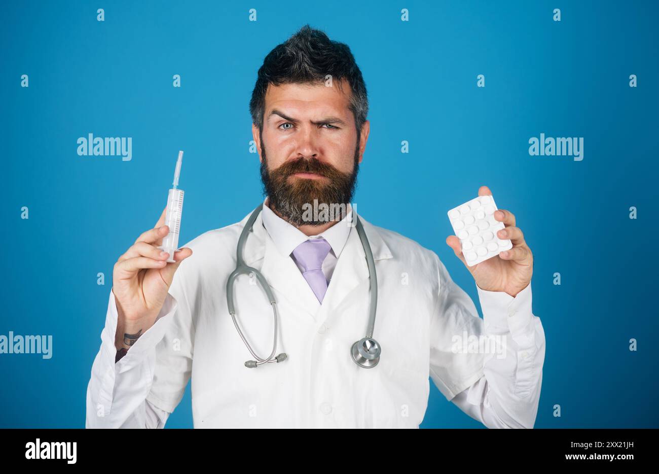 Serious professional male doctor with syringe and pills in blister pack ...