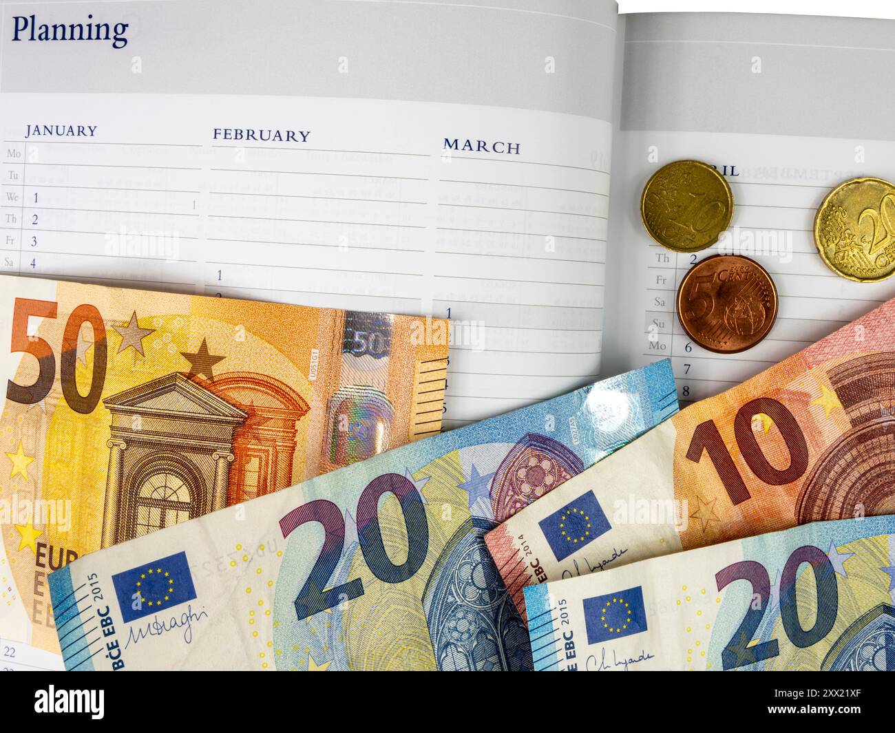 Close-up of Euro banknotes and coins arranged on an open calendar with ...