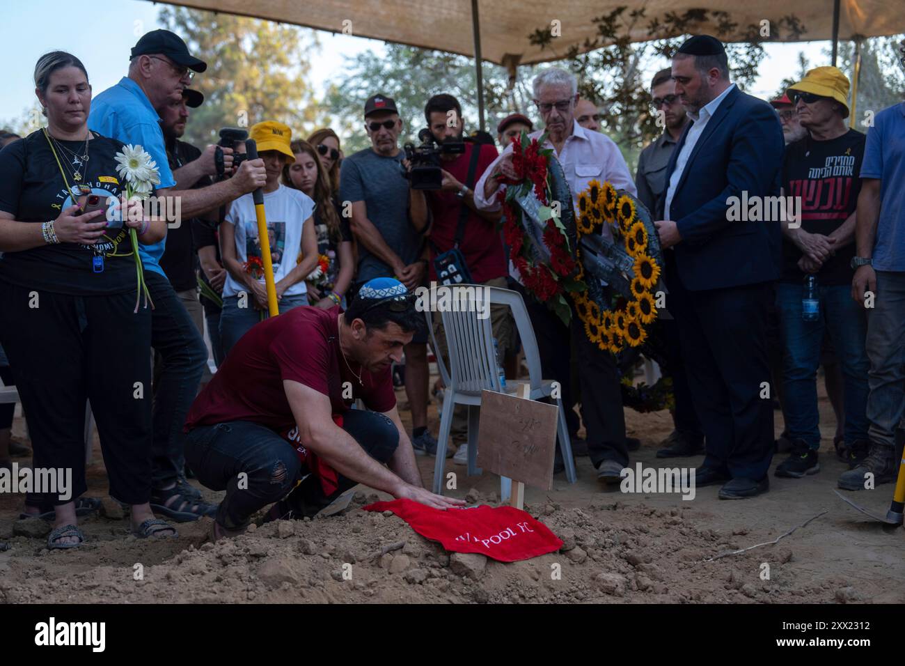 A man places a Liverpool football team scarf on the grave of Avraham ...