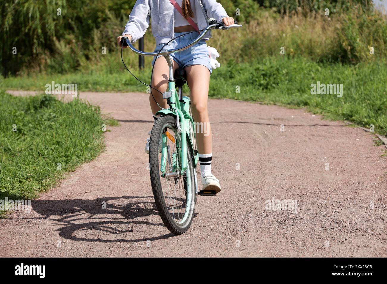 Girl in jeans shorts riding the bicycle in summer park. Cycling and ...