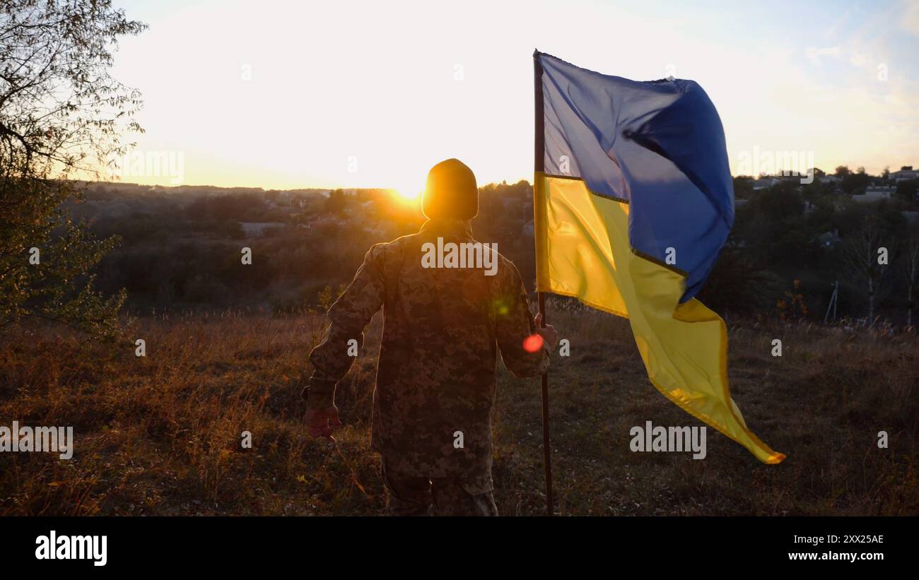 Young man in military uniform jogs with waving flag of Ukraine at ...