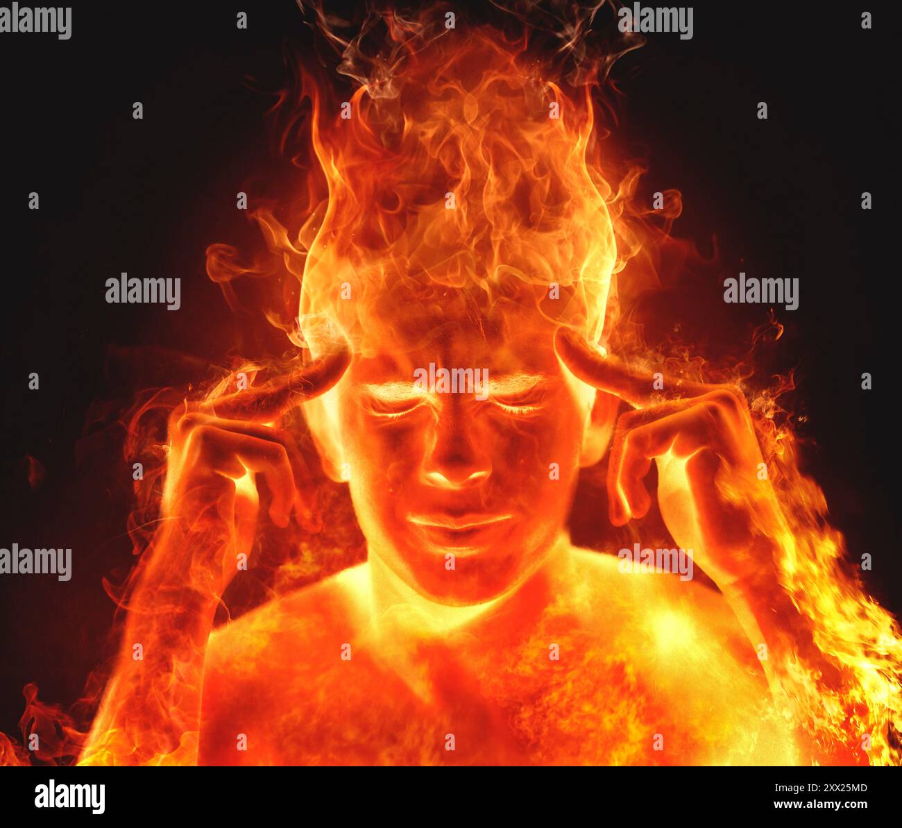 Conceptual man on fire with his eyes closed and hands on his temples ...