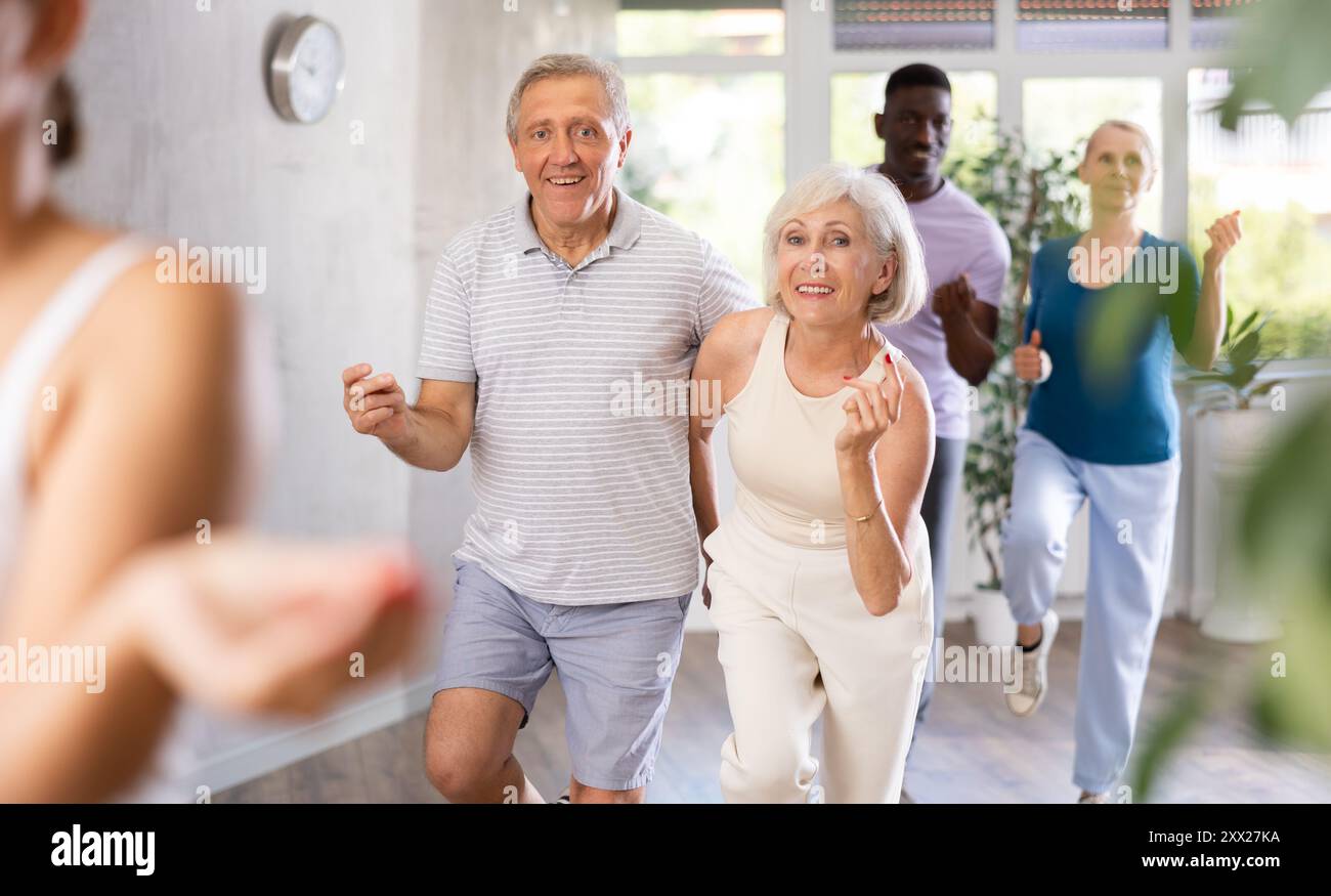 Aged man and woman dancing jive during group training Stock Photo - Alamy
