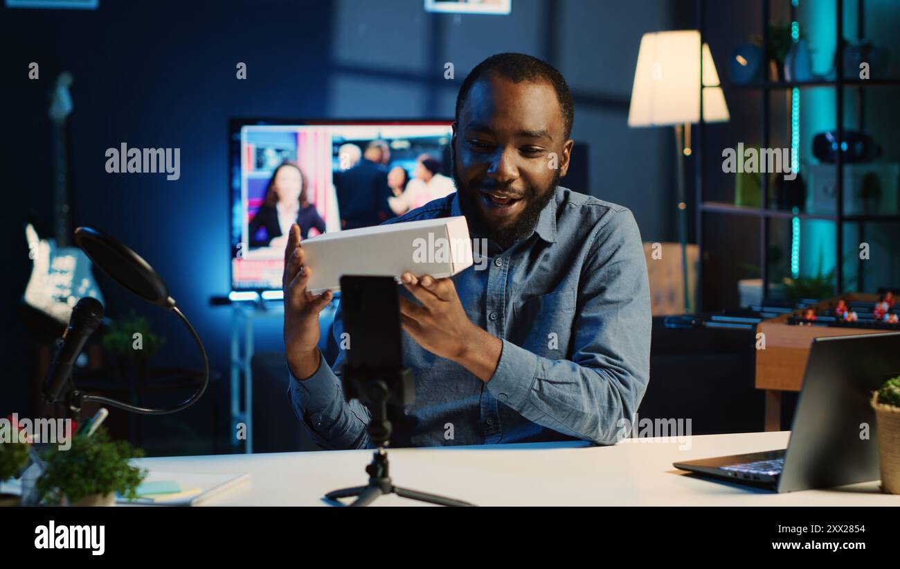 Tech content creator filming packaged product unboxing in neon lights ...