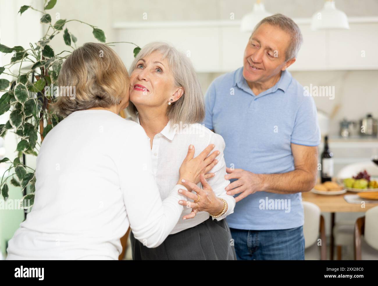 As two elderly woman meet, they exchange warm greeting by embracing ...