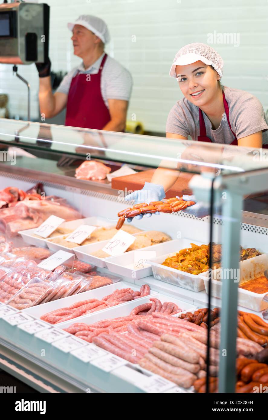 The saleswoman offers fresh baby chorizo sausages at the butcher shop ...