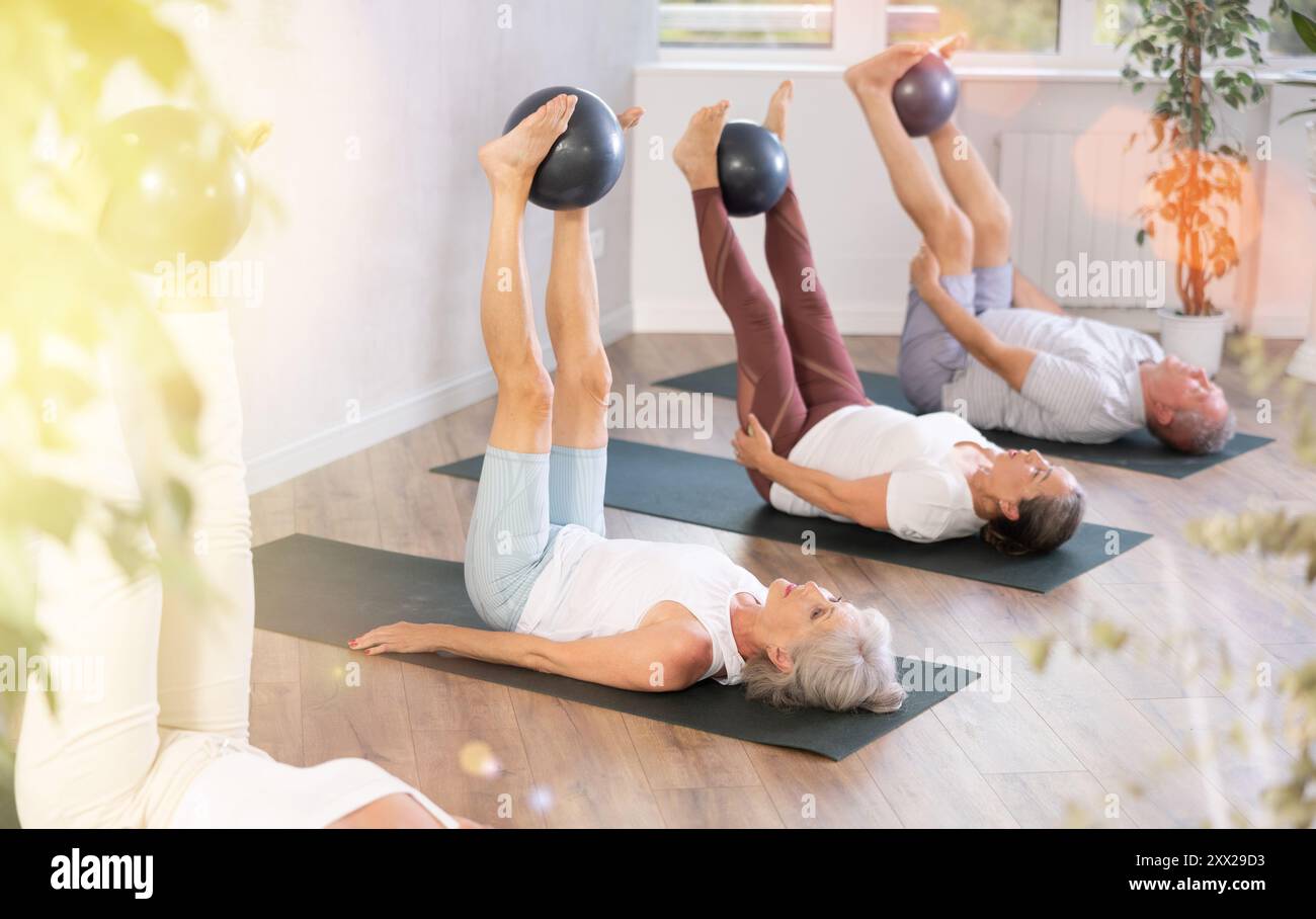 Visitior yoga class lying on back, raised legs perpendicular to floor ...