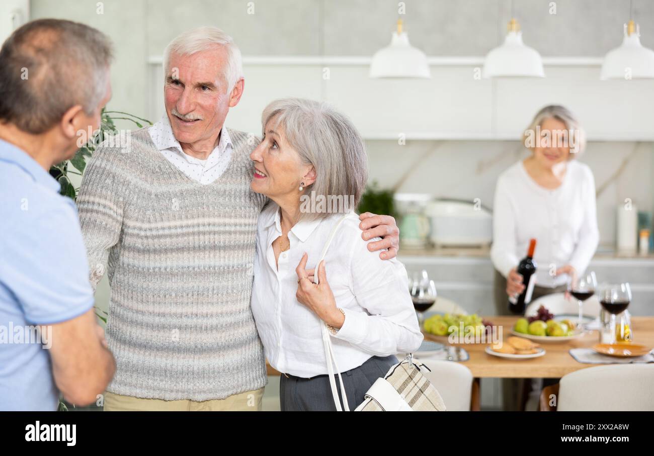 In home, mature man shake hands with couple, say hello, inviting to ...