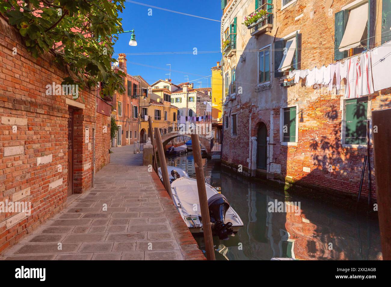A Venetian canal lined with brick buildings, a small boat, and laundry ...