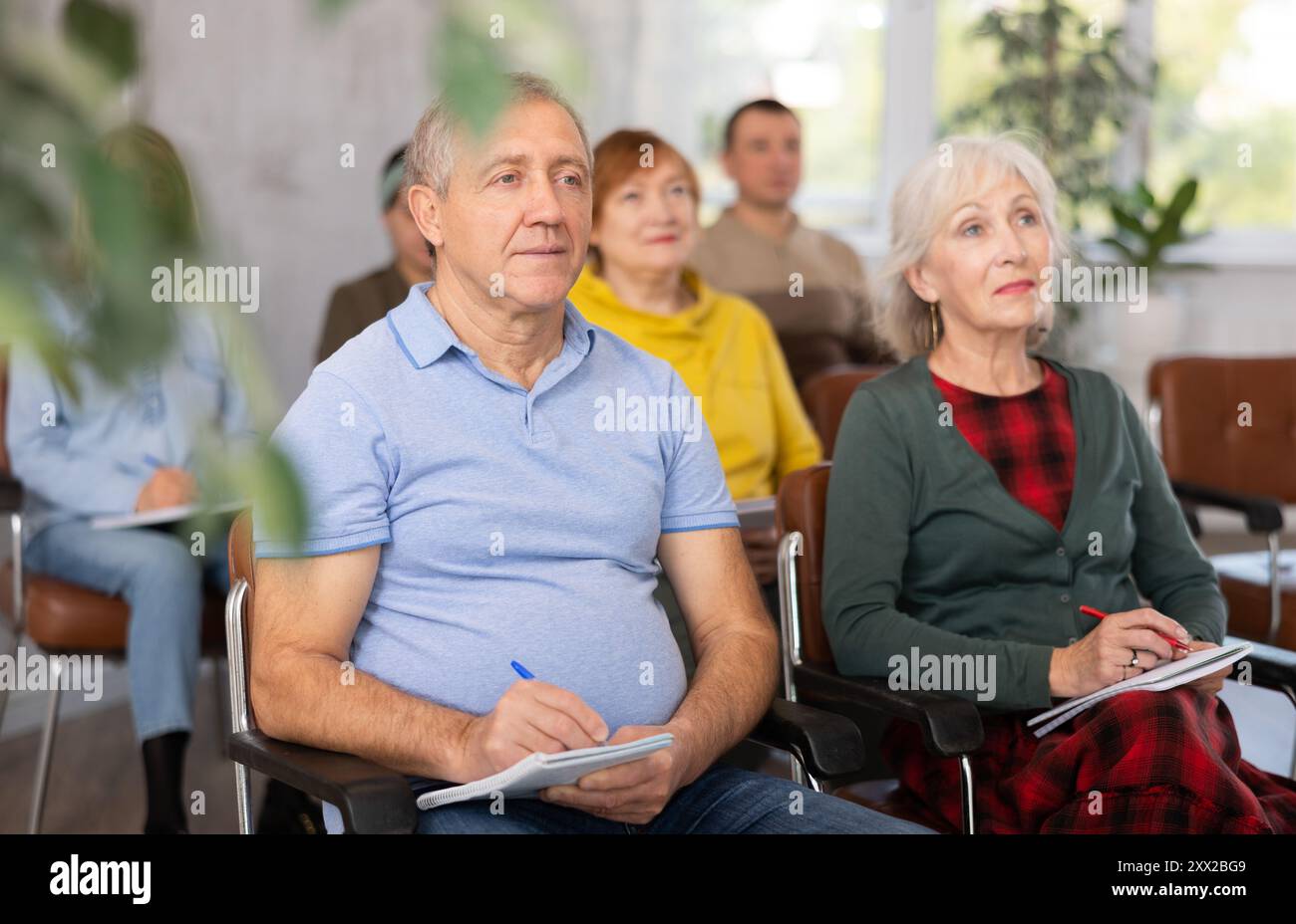 Motivated older man listening to lecture in auditorium with group Stock ...