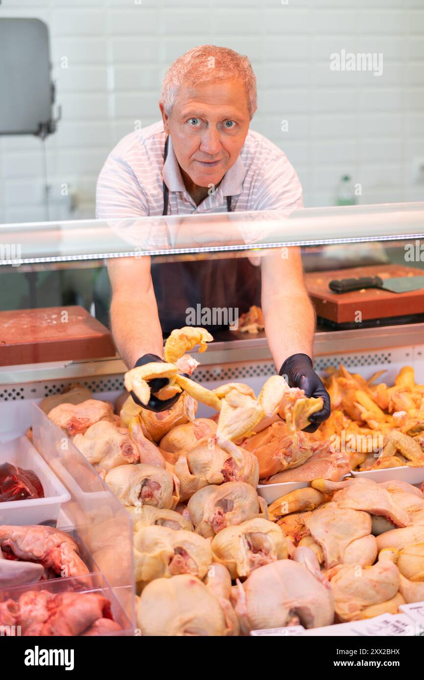 Senior man butcher shop owner offering raw chickens Stock Photo - Alamy