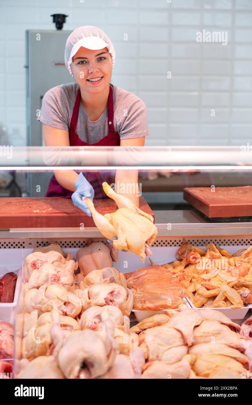 Female seller took out dressed chicken carcass from case refrigerator ...