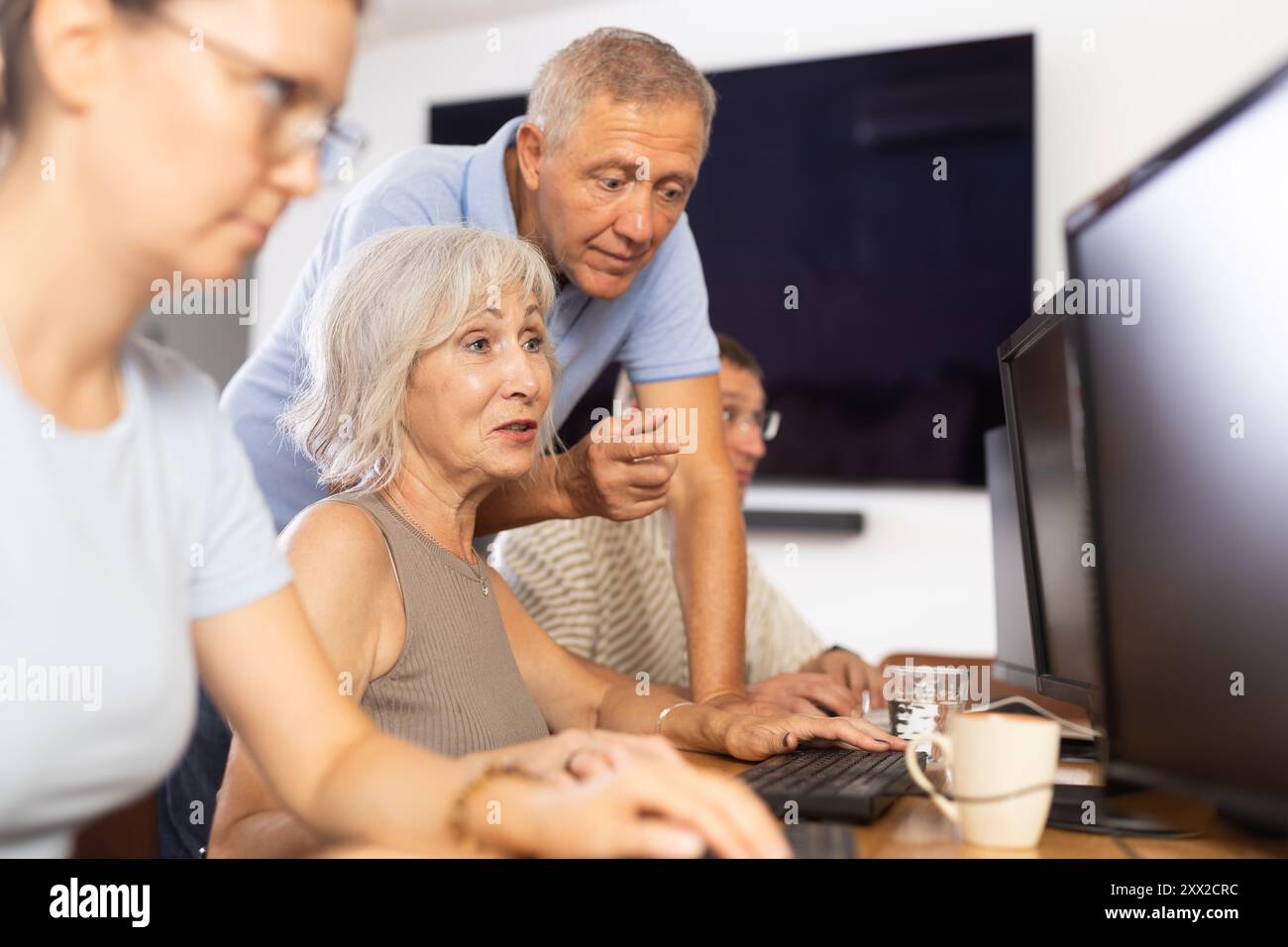 Friendly elderly computer course teacher helping woman learn computer ...
