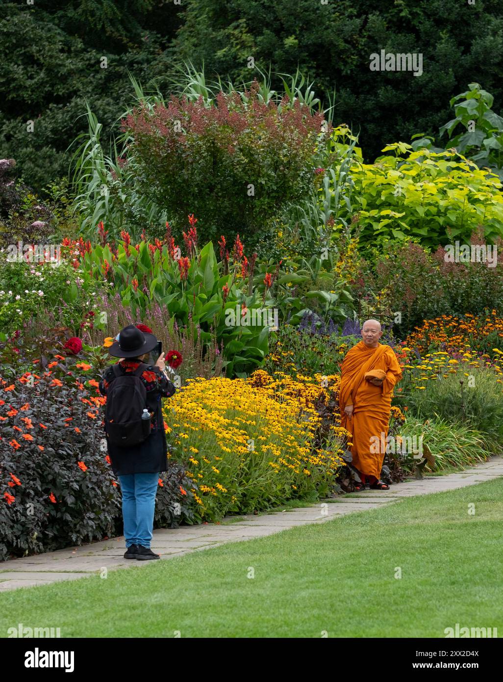 Buddhist monk wearing traditional orange robes is photographed by a ...