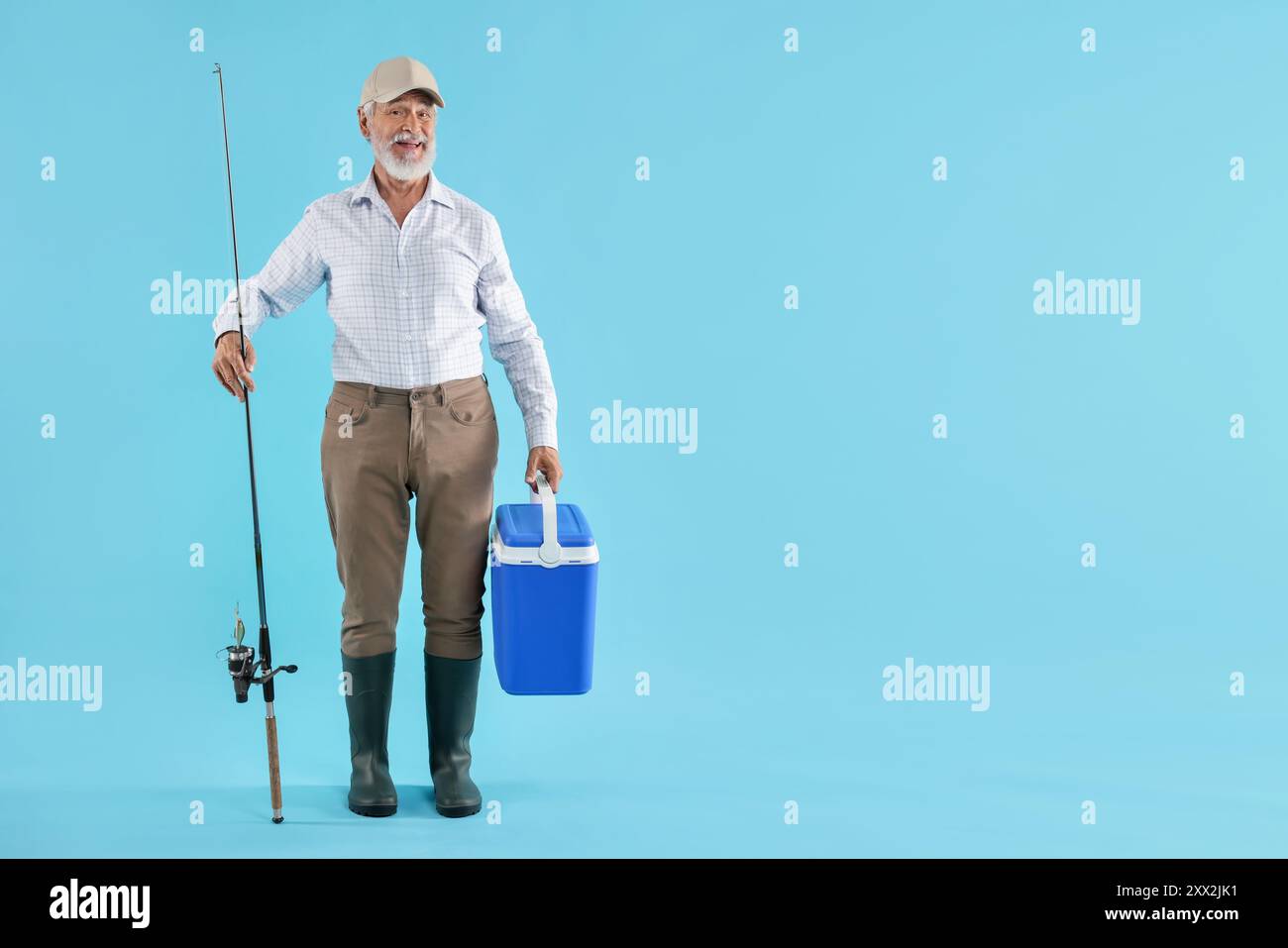Fisherman with rod and cool box on light blue background Stock Photo ...