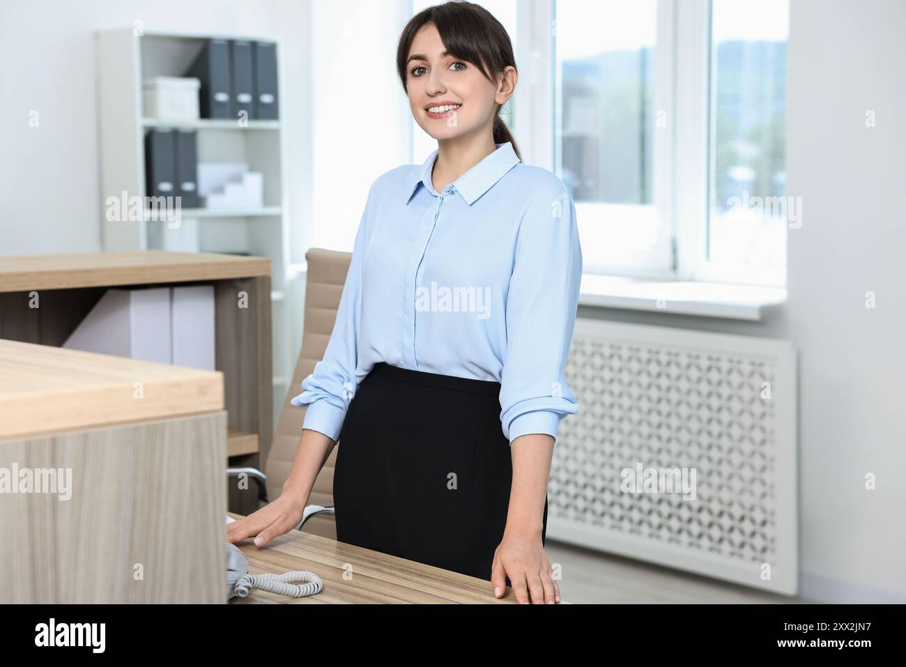 Portrait of receptionist at wooden desk in office Stock Photo - Alamy