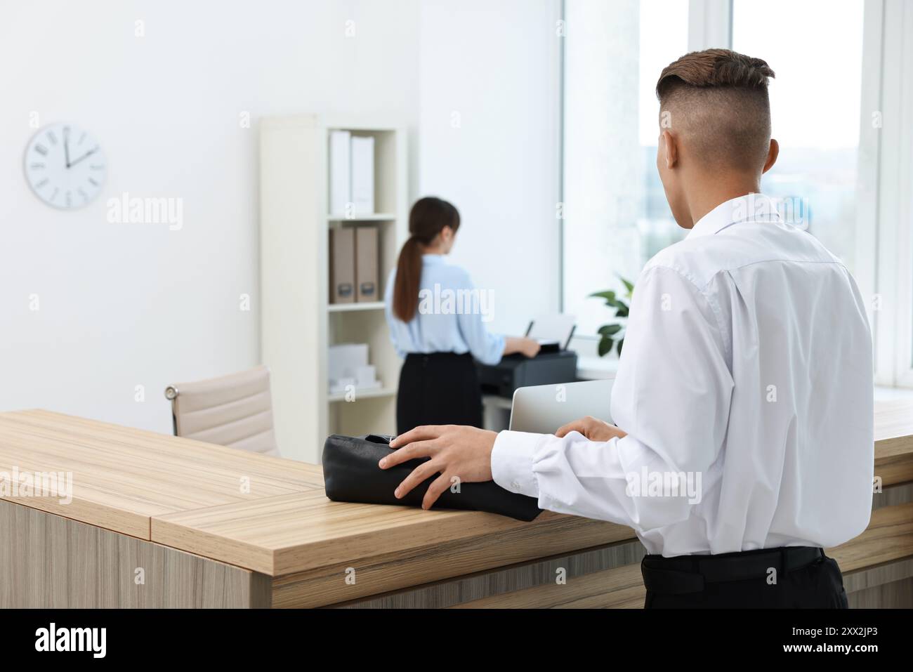 Professional receptionist and client in office, back view Stock Photo ...