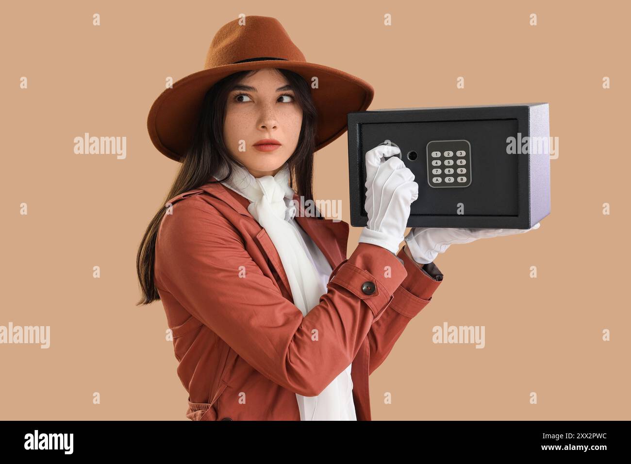 Female spy breaking into safe on beige background Stock Photo - Alamy