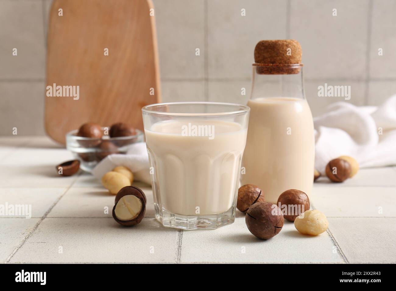 Glass and bottle of fresh macadamia milk on white tile background Stock ...