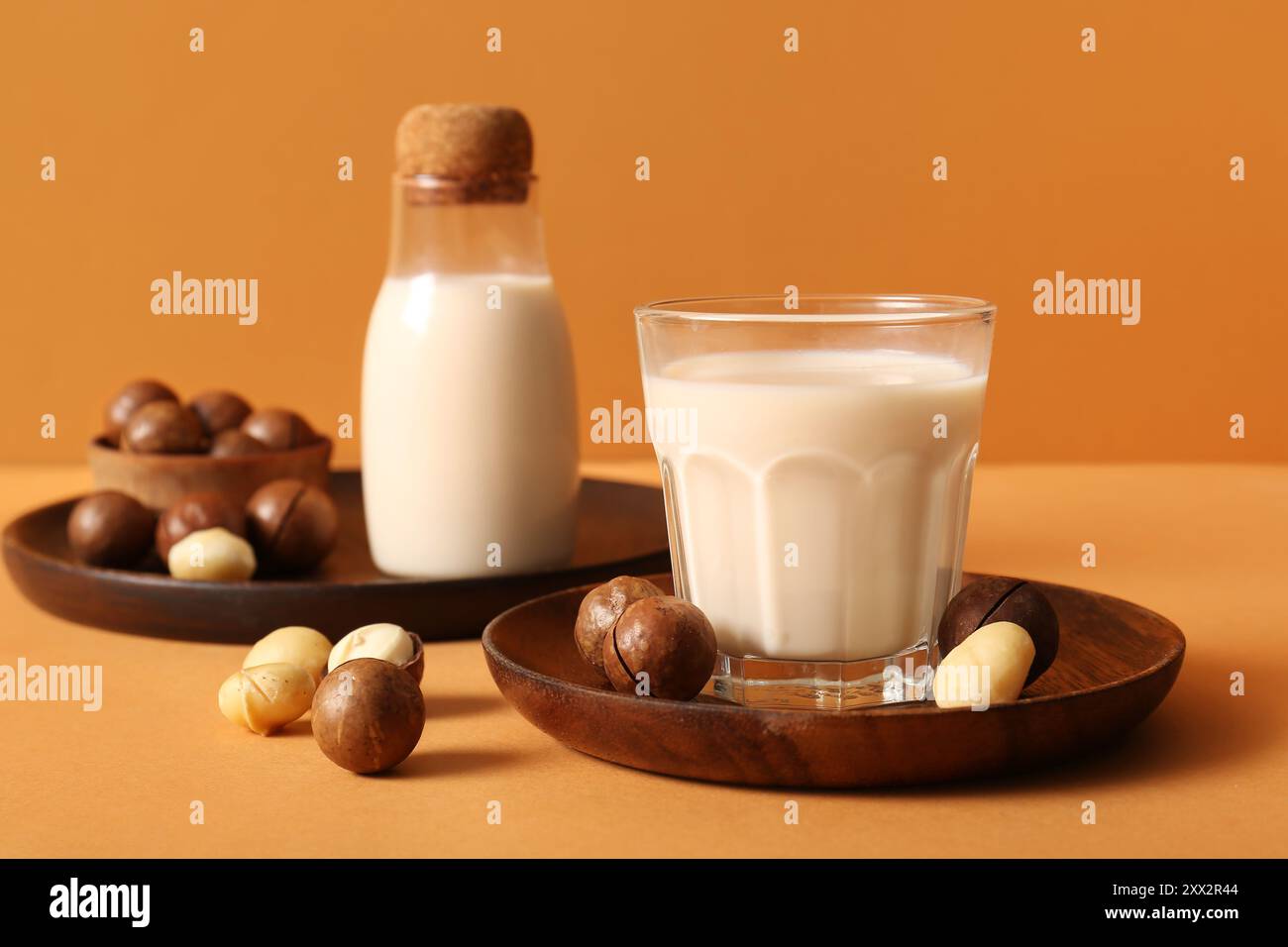 Glass and bottle of fresh macadamia milk on brown background Stock ...
