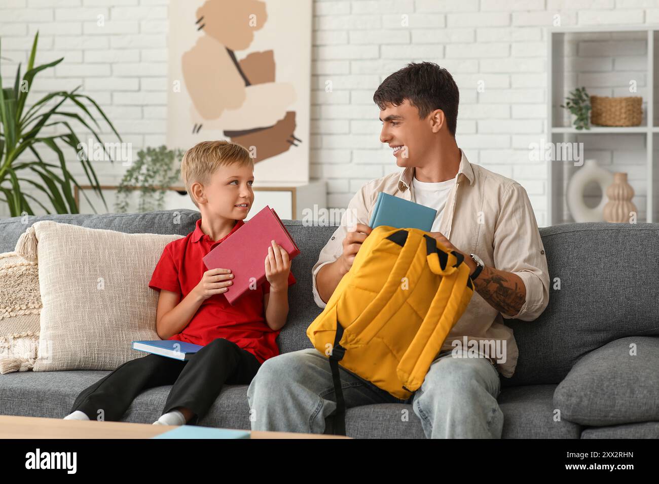 Father packing backpack with books for his little son at home Stock ...