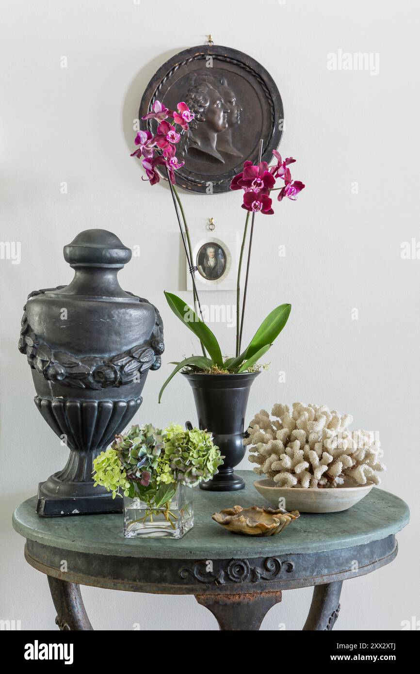Still life of art objects and urn on round table Stock Photo - Alamy