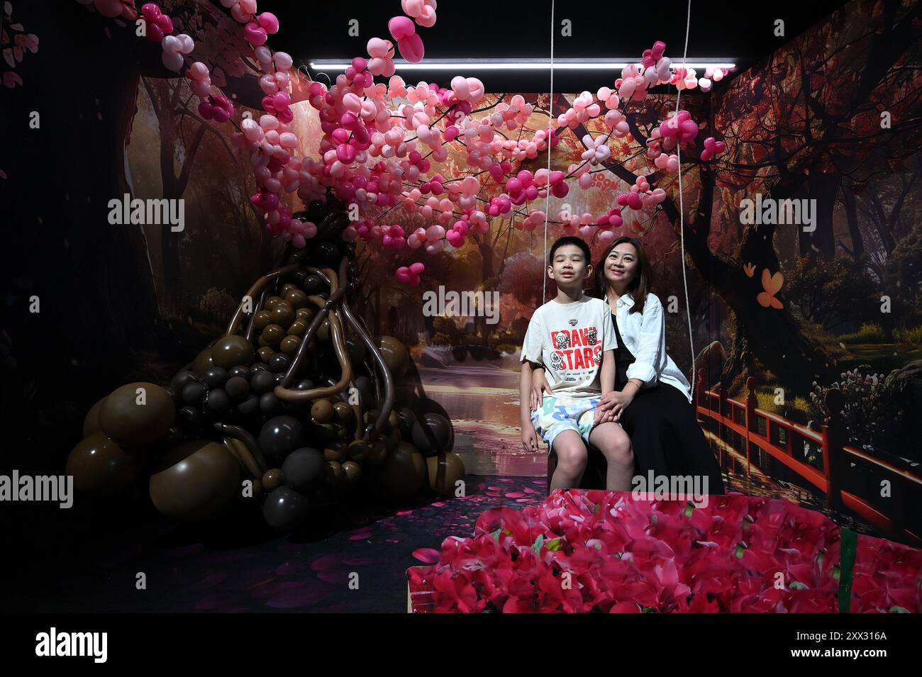 A woman and her sone sit in a cherry tree diorama made of latex balloon ...