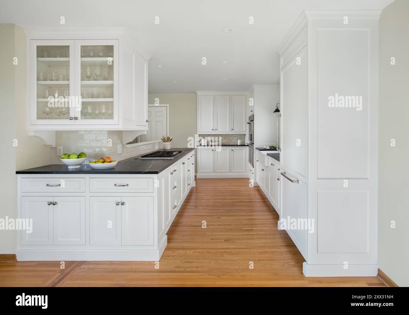 Entrance to white kitchen showing glass cabinets in front and view ...