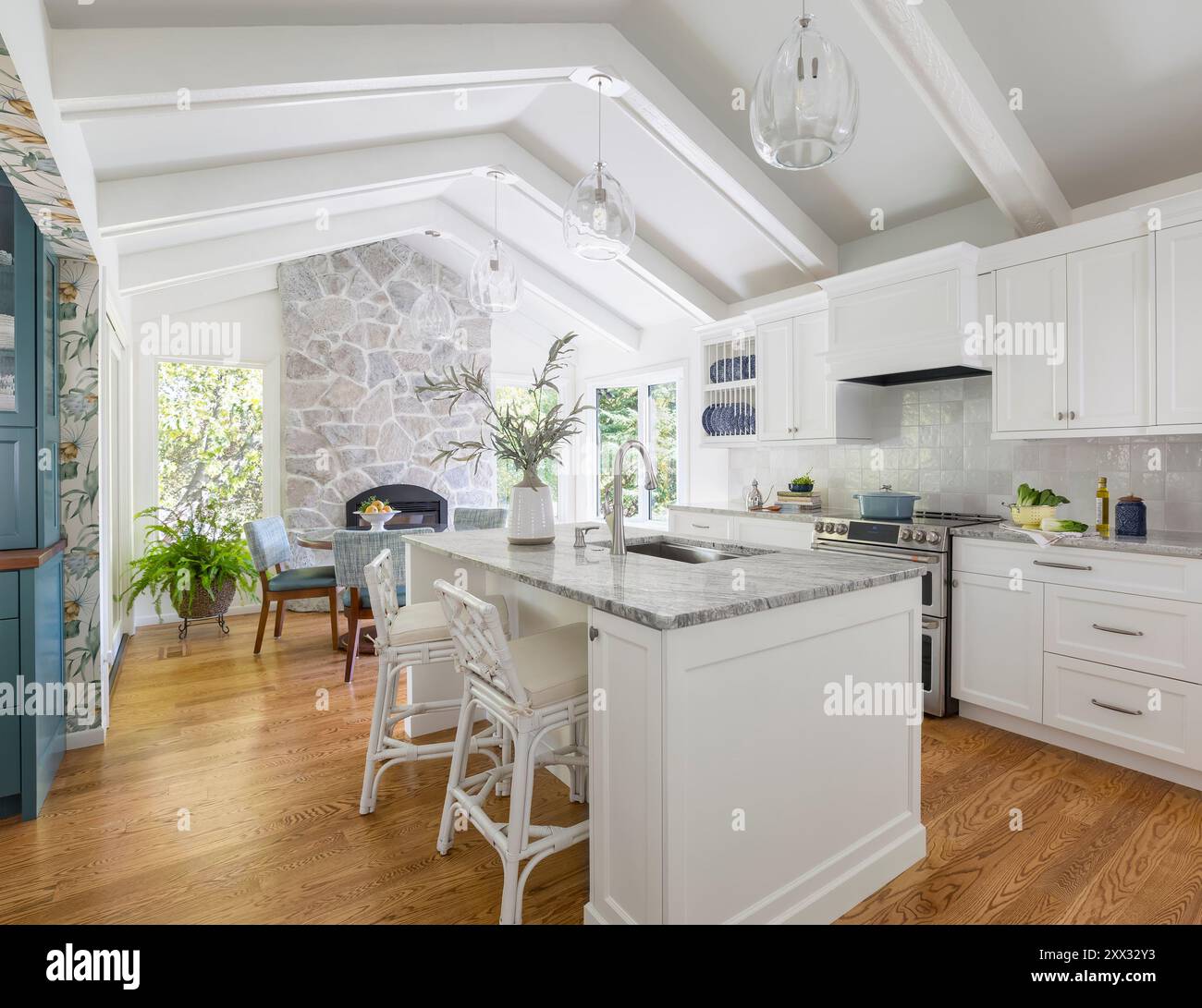 White kitchen with beamed ceiling and small dining area by stone ...