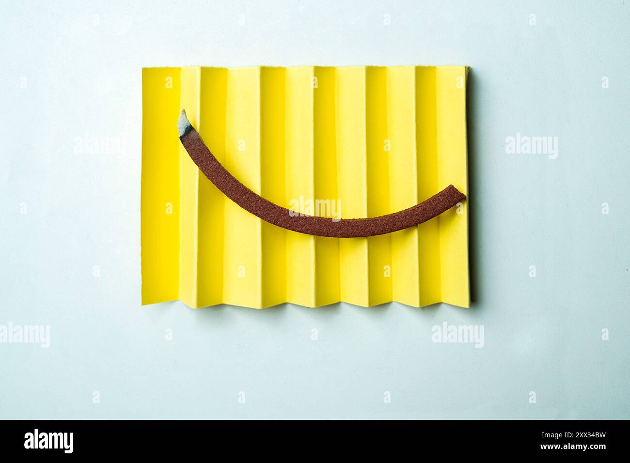 A yellow piece of paper with a mosquito coils on it. A brown object is ...