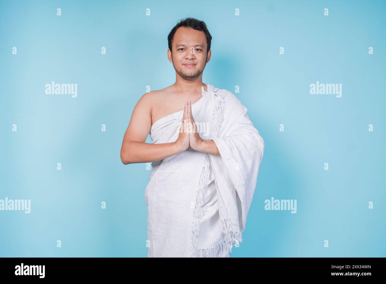 Attractive young Asian Muslim man wearing ihram gesturing traditional ...