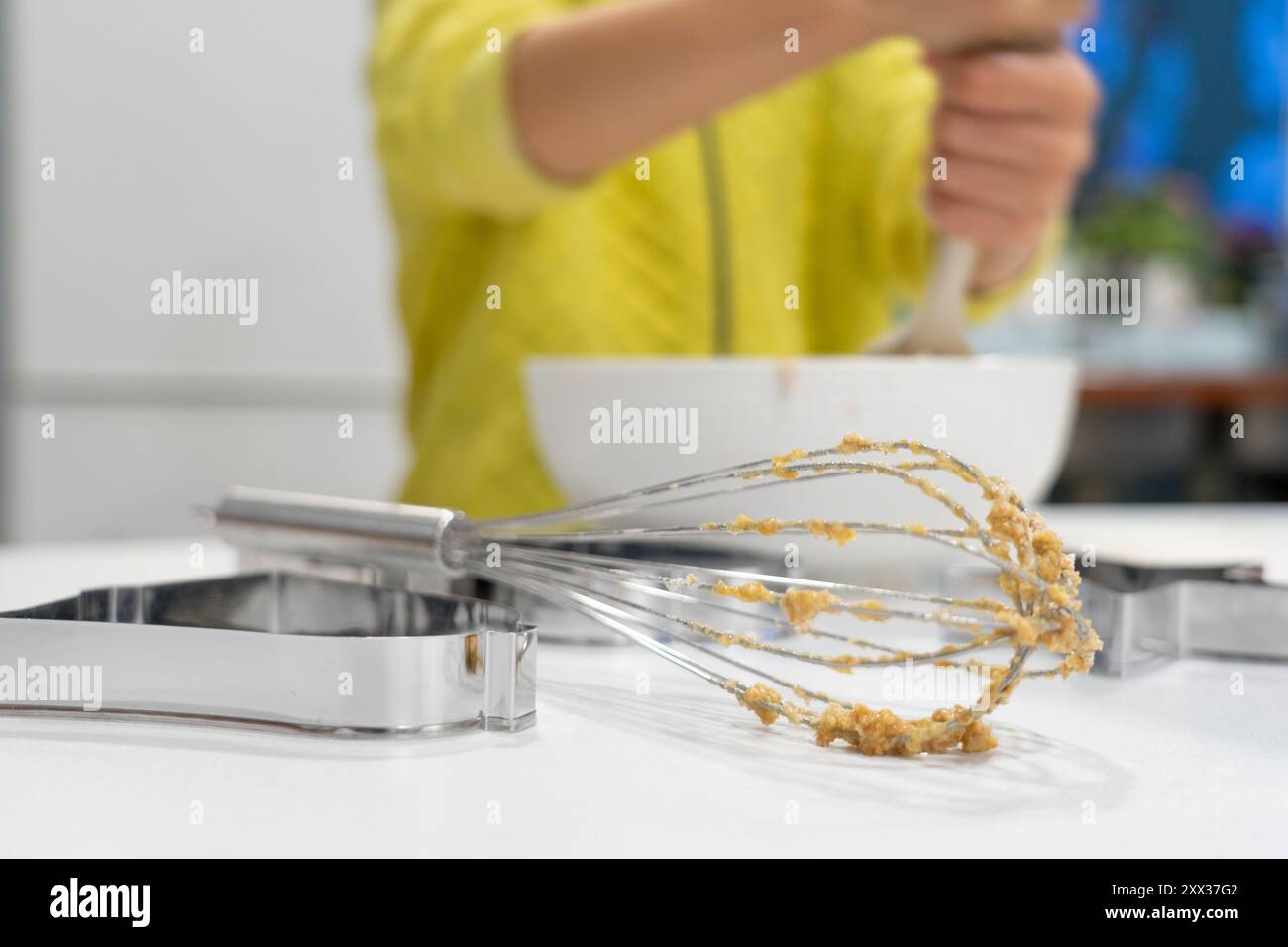 Whisks stained with dough seen from close up and an unrecognizable boy ...