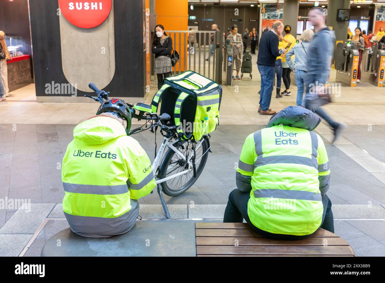 Uber eats delivery riders take a lunch break in Chatswood Sydney with electric e bike beside ...