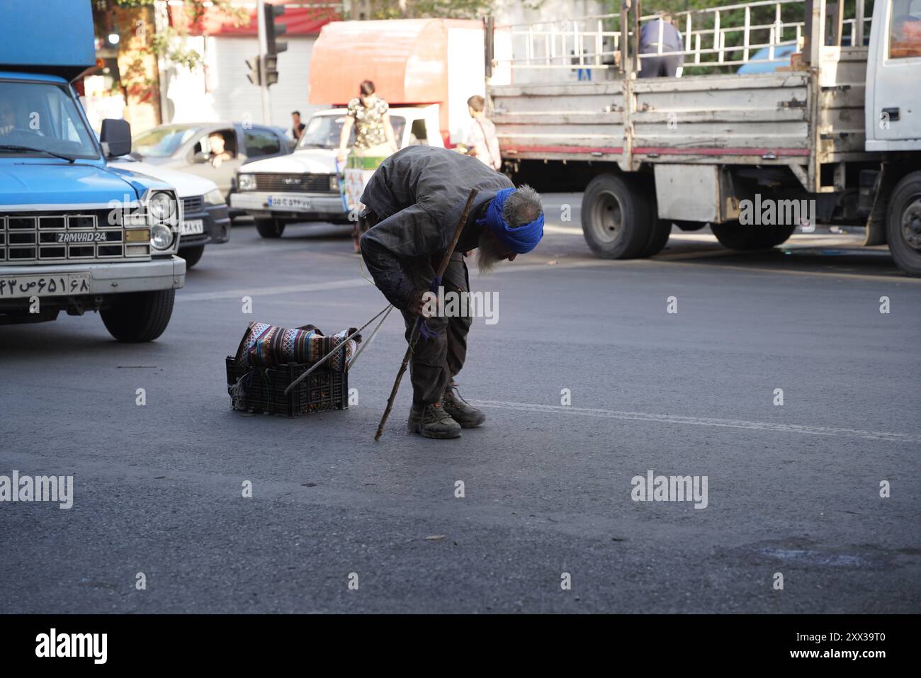 A frail old man with a hunched back and torn clothes walks slowly, his ...