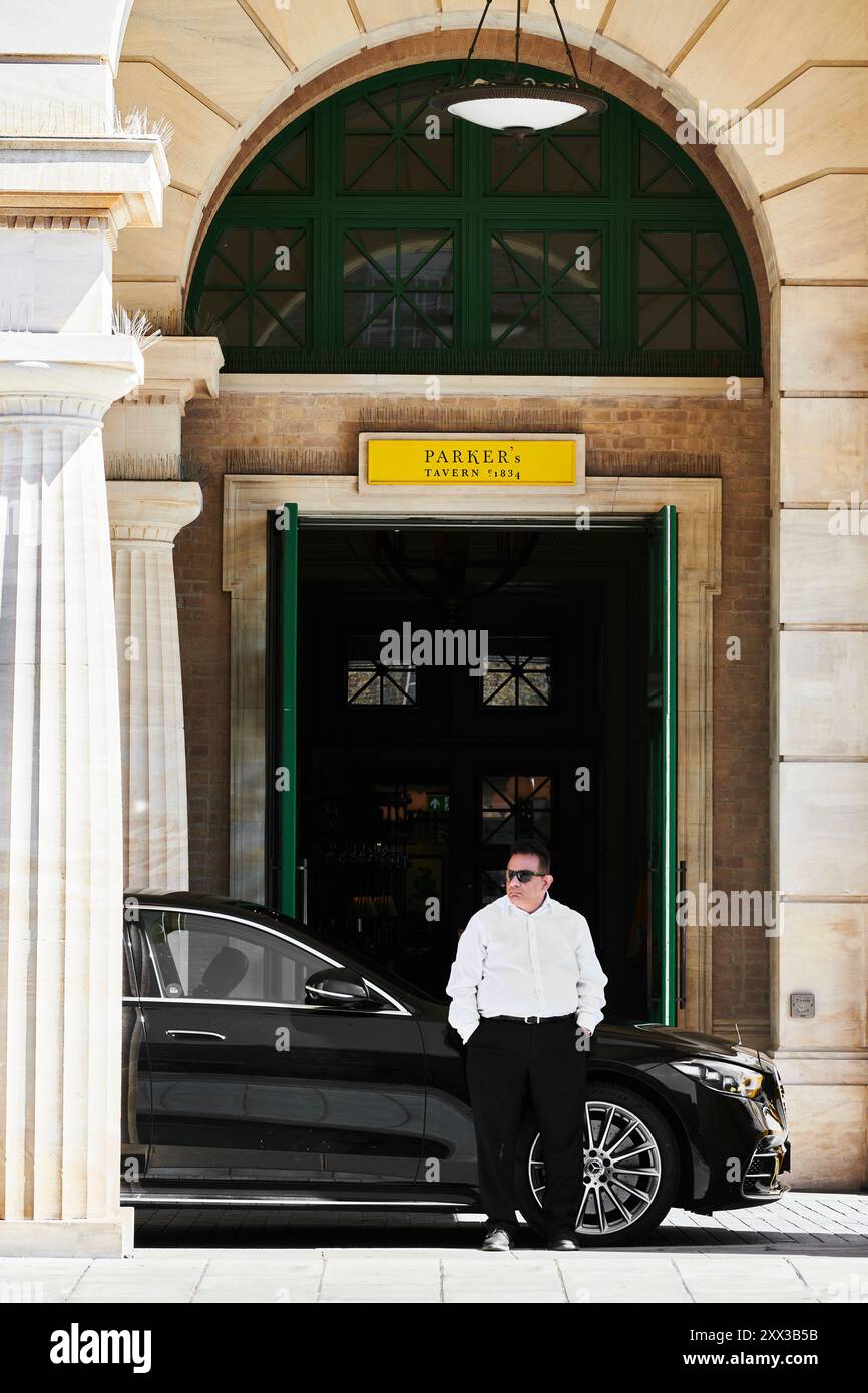 Chauffeur lounges against smart car parked outside the door to Parker's ...