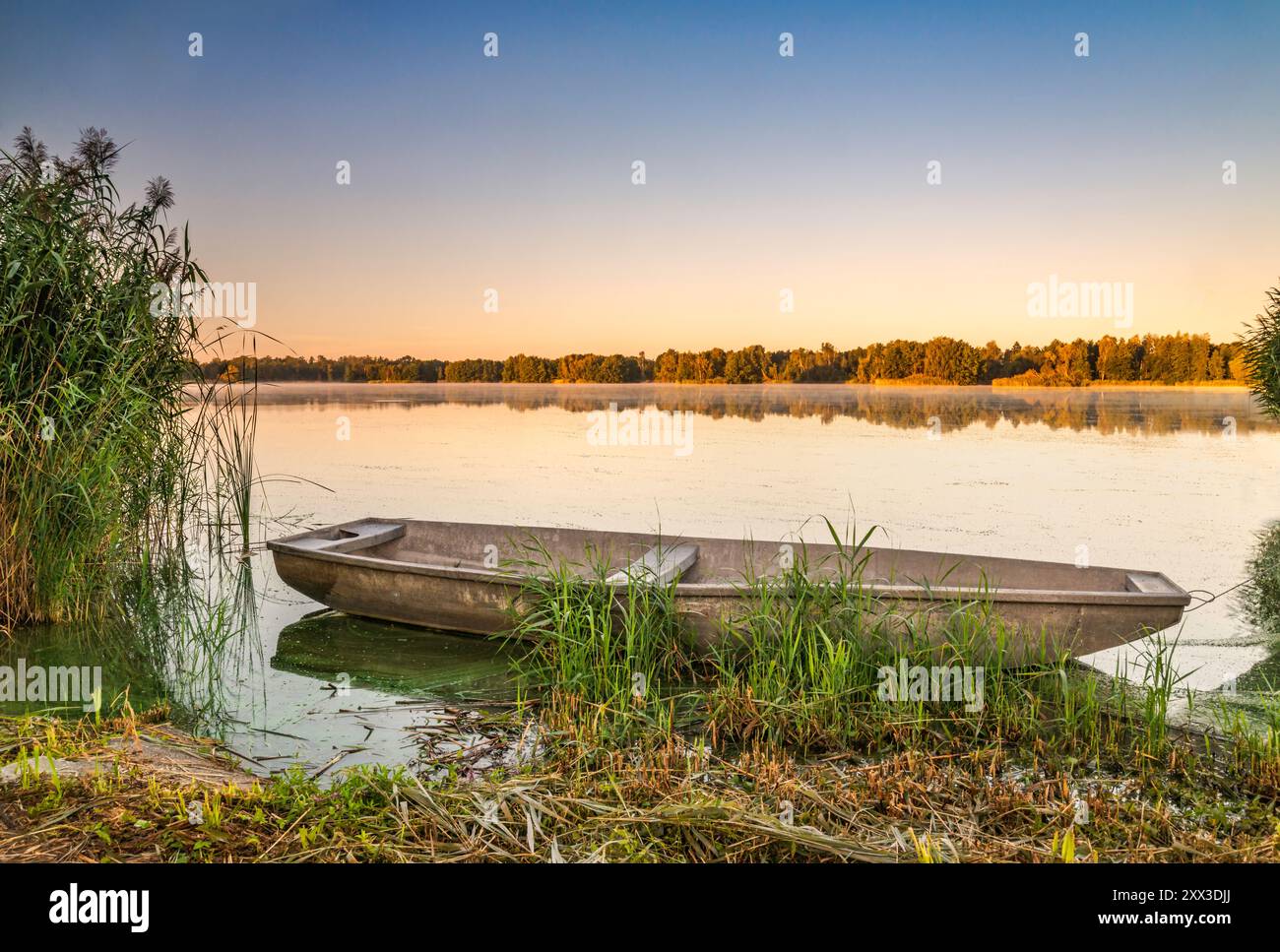 Boat tied up at Staw Nowy, at sunrise, seen from dike between ponds ...