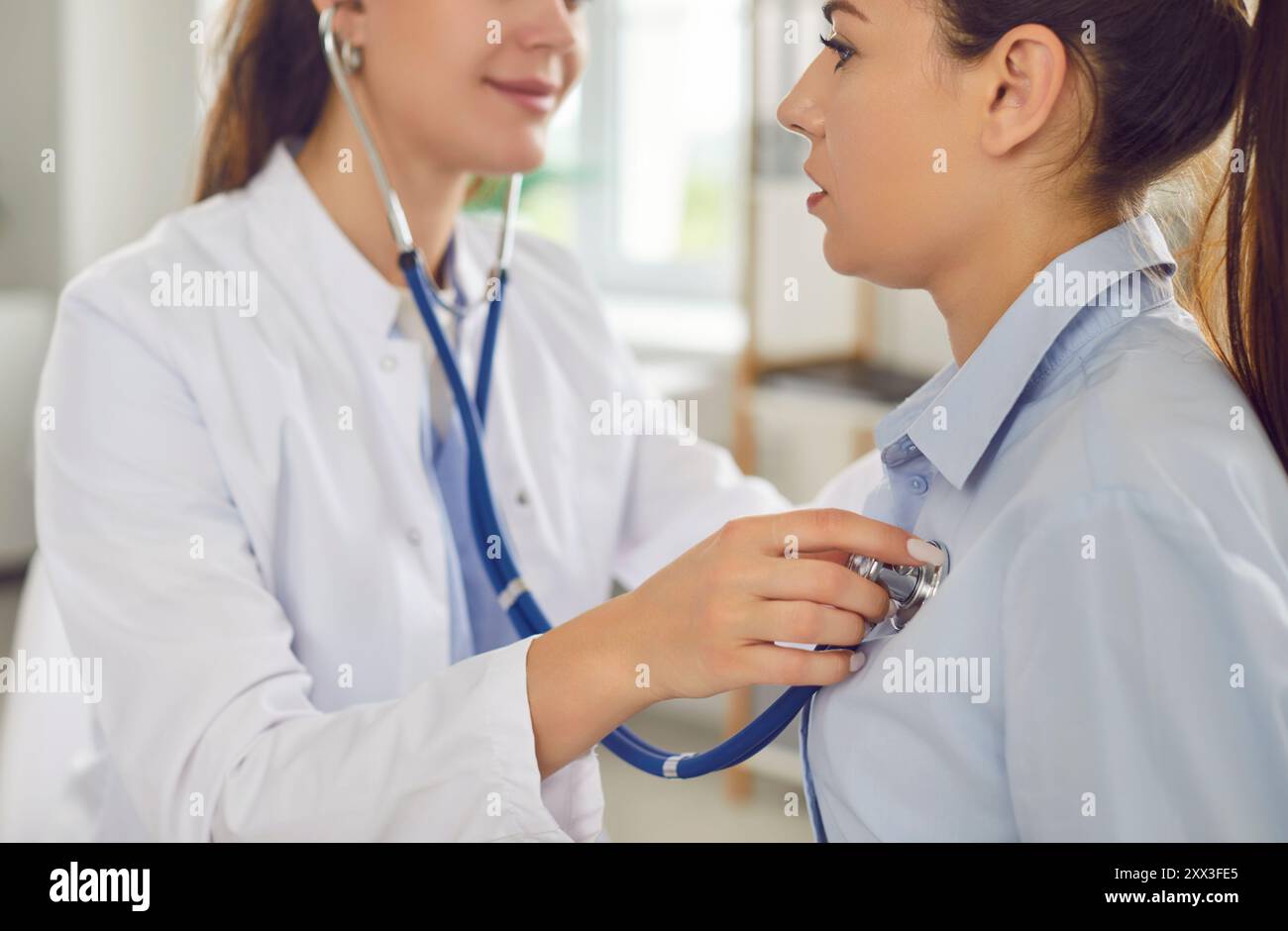 Female doctor uses stethoscope to examine young girl patient to check ...