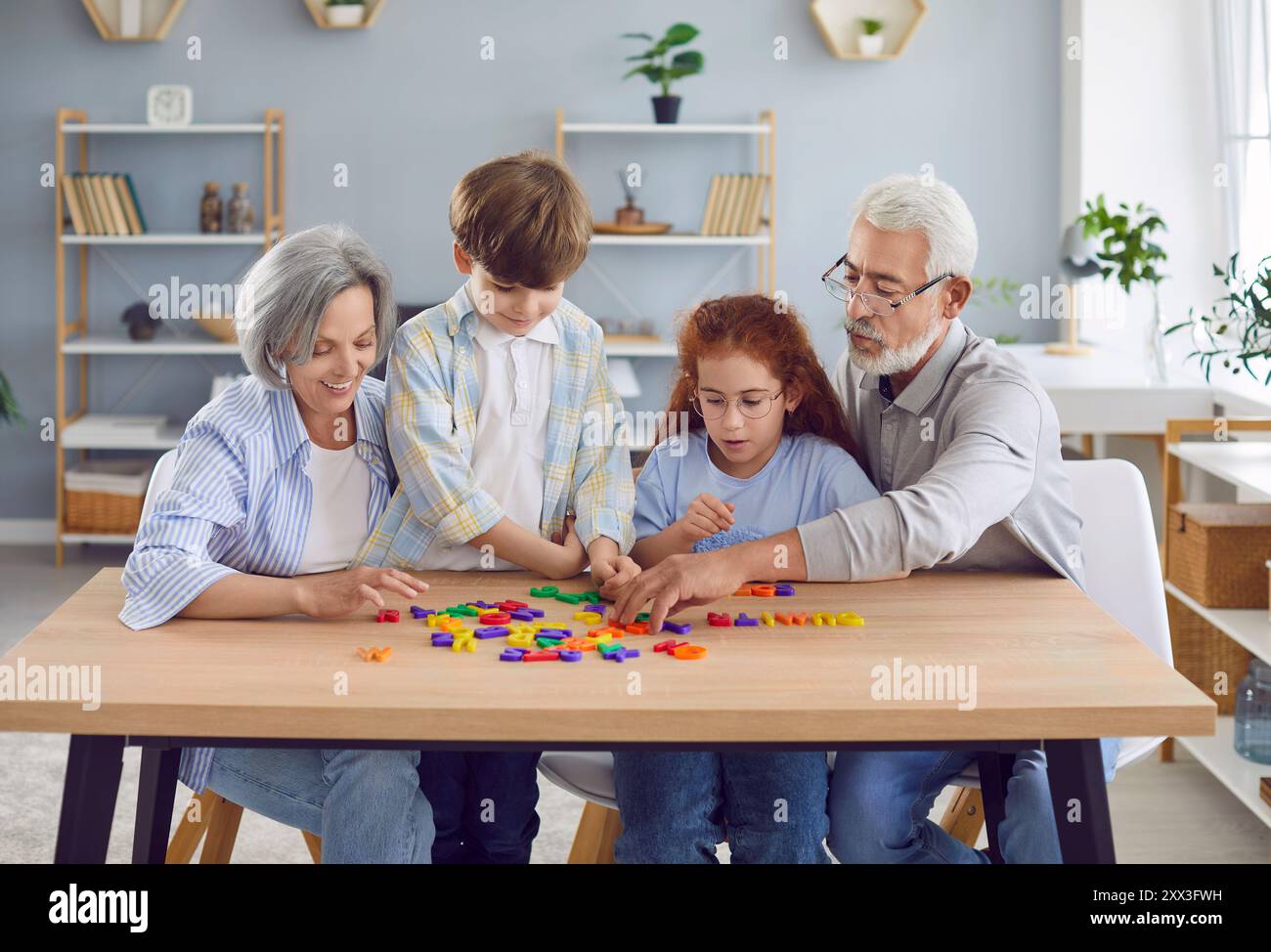 Grandparents teaching their grandchildren alphabet making words of ...