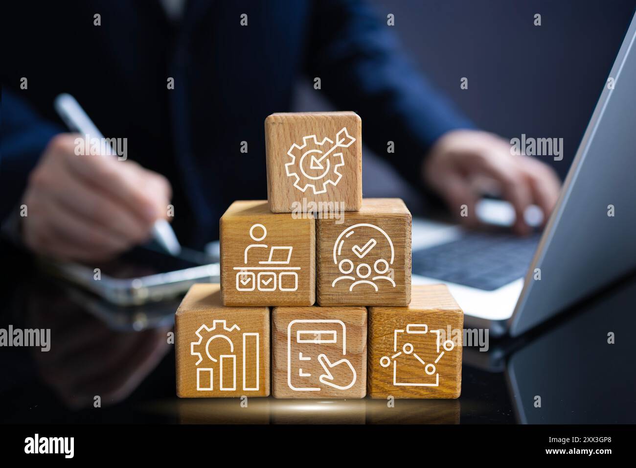 A professional works on a laptop, with wooden blocks in the foreground ...