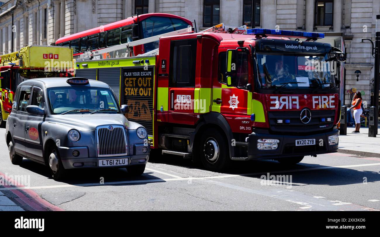 London - 06 14 2022: Fire truck and a taxi stopped at traffic lights on ...