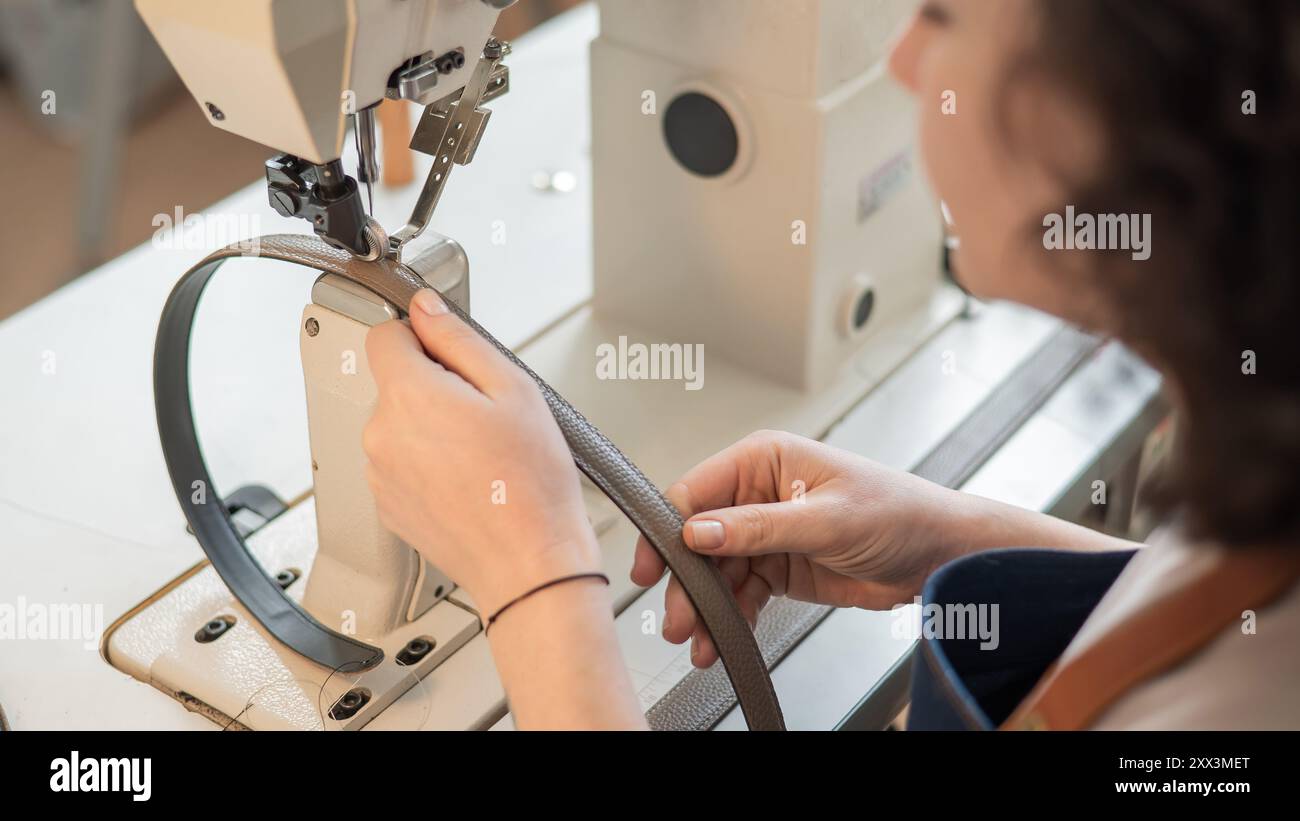 A woman tanner sews a leather belt on a sewing machine Stock Photo - Alamy