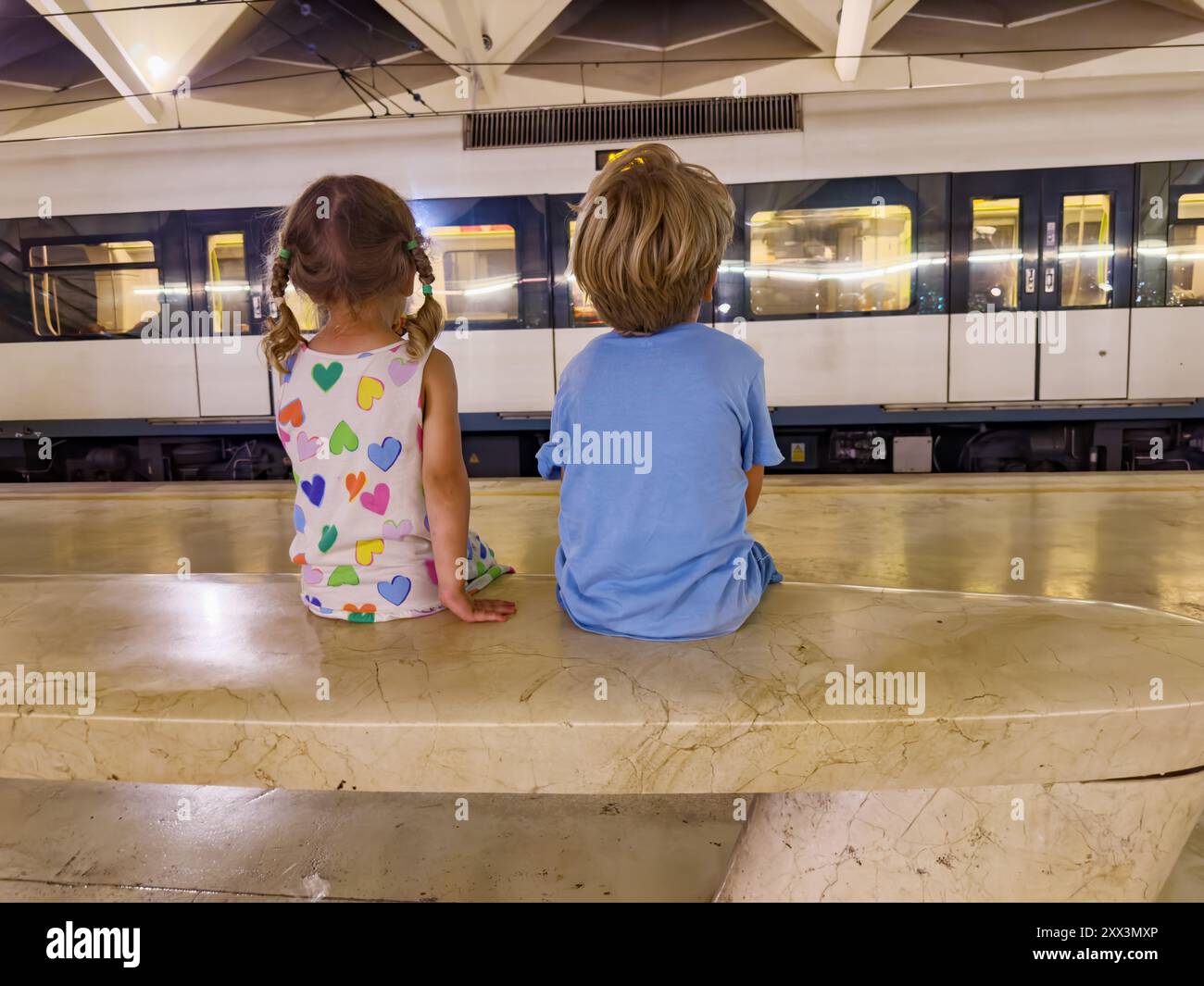 Children sit on bench, watch train at station, Valencia, Spain Stock ...