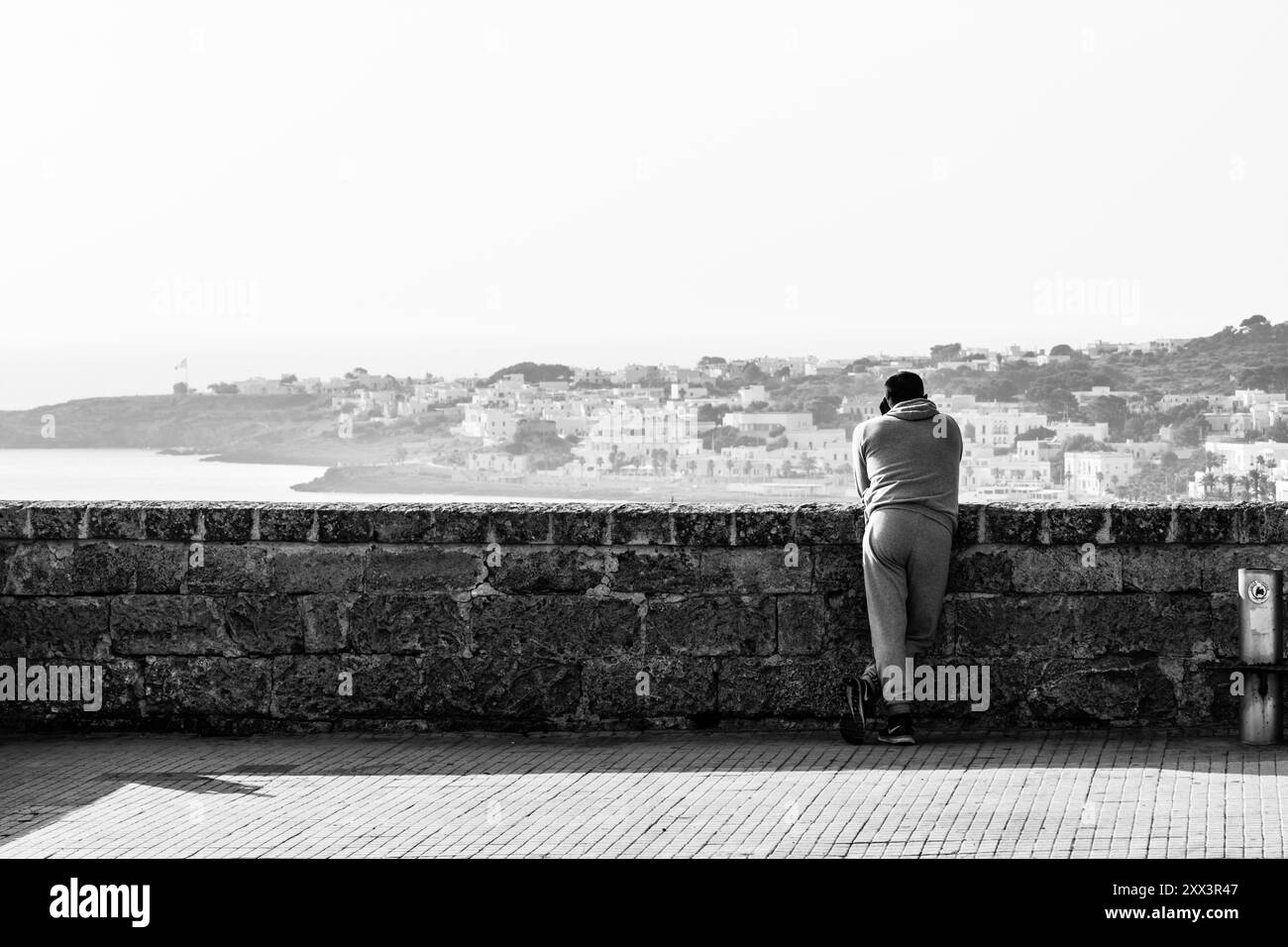 A solitary adult man leaning against a low wall observes the panorama ...