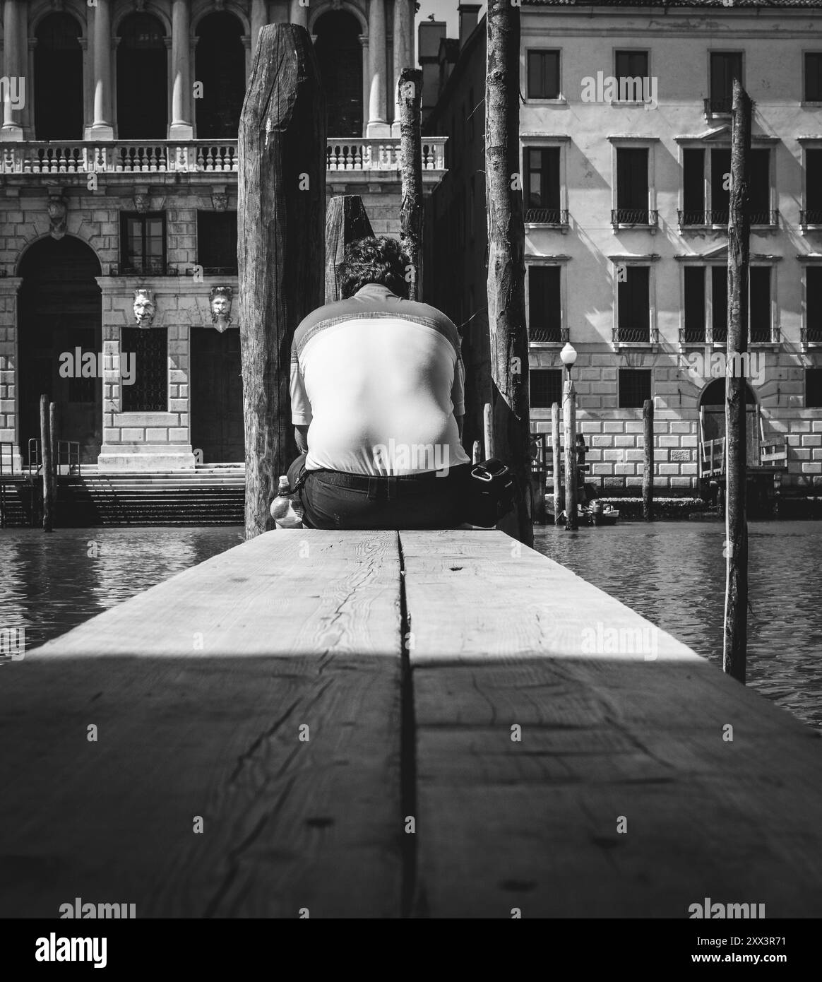 A fat man sits alone on a dock in a canal in Venice Stock Photo - Alamy