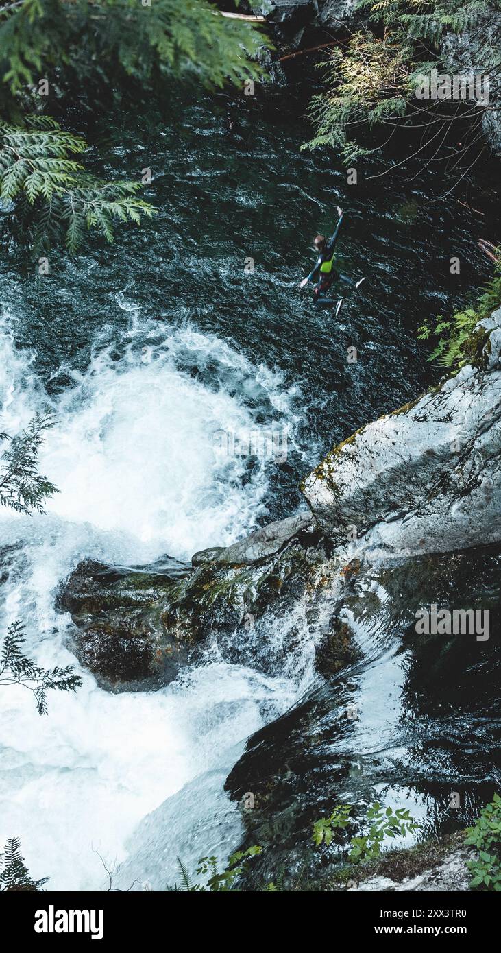 A cliff jumper captured mid-air at Twin Falls in Lynn Canyon Park, a ...