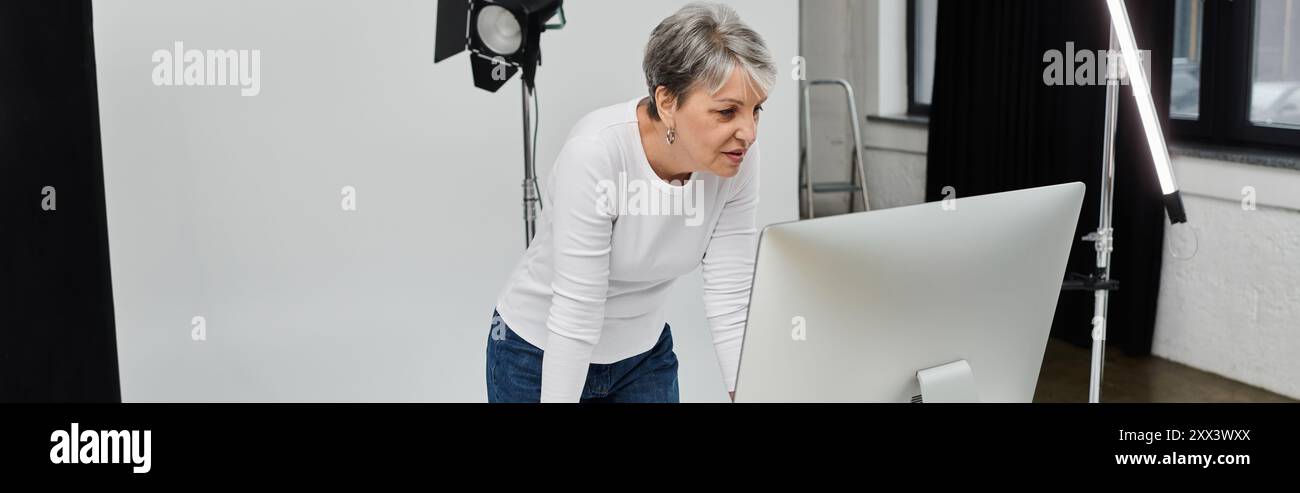 A woman in a white shirt bends over a computer screen, likely reviewing ...