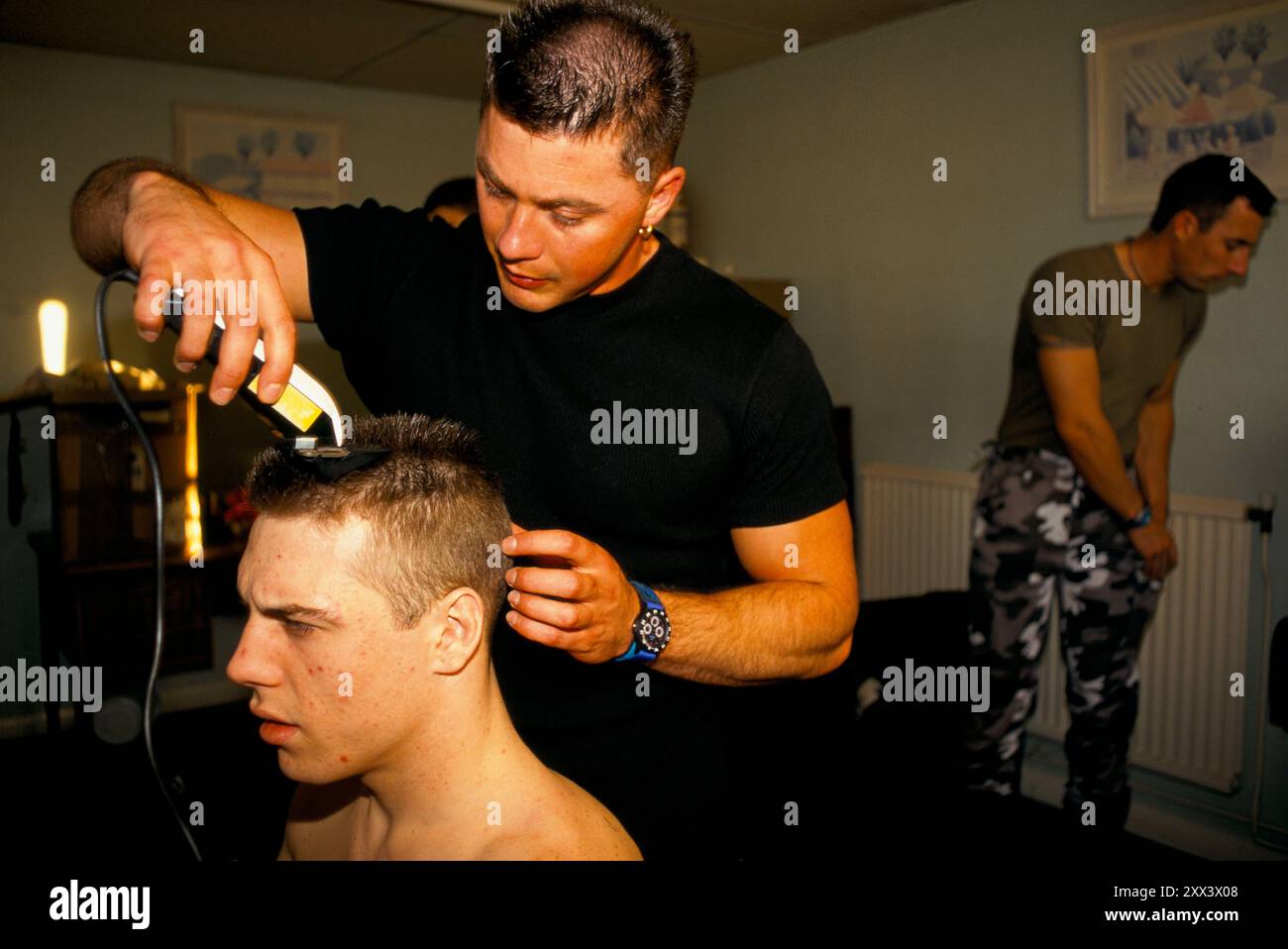 Man shaving the head of another man with an electric razor. Both men ...