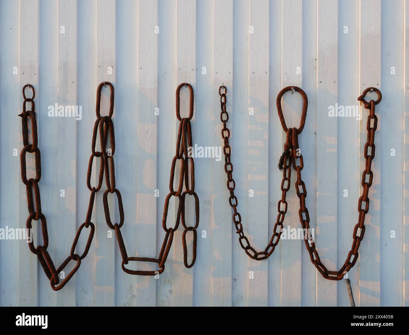 a white wooden wall in the harbor with various iron chains hanging on ...